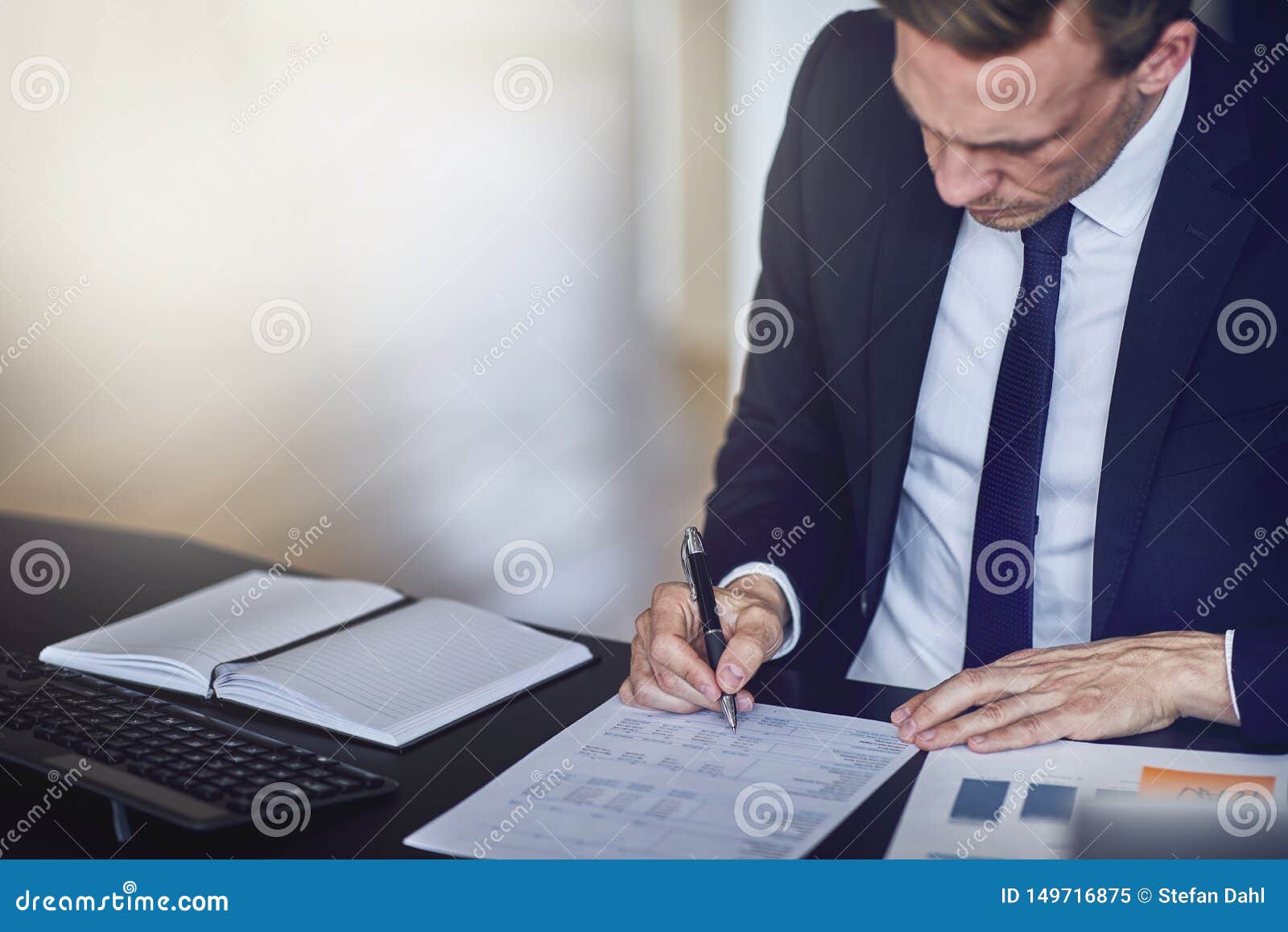 Businessman Sitting at His Office Desk Looking Over Documents Stock ...