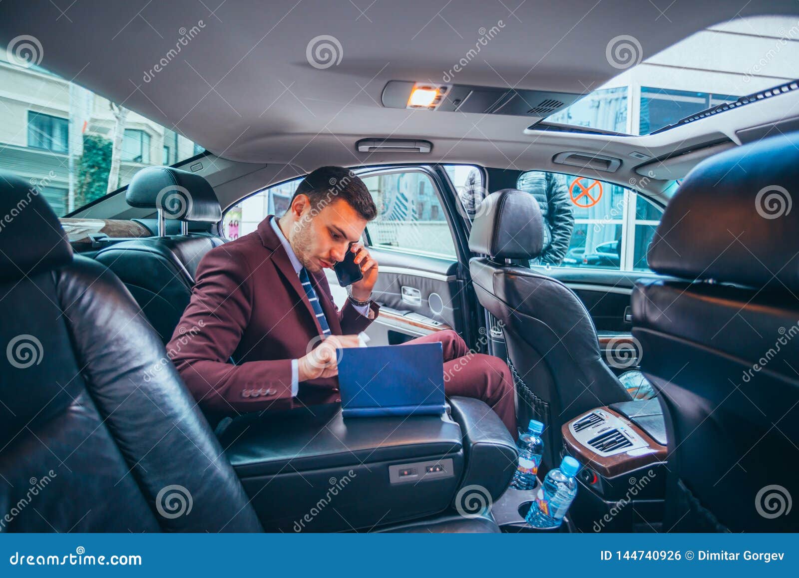 Businessman Sitting in a Limo while Talking on His Phone Reading His ...