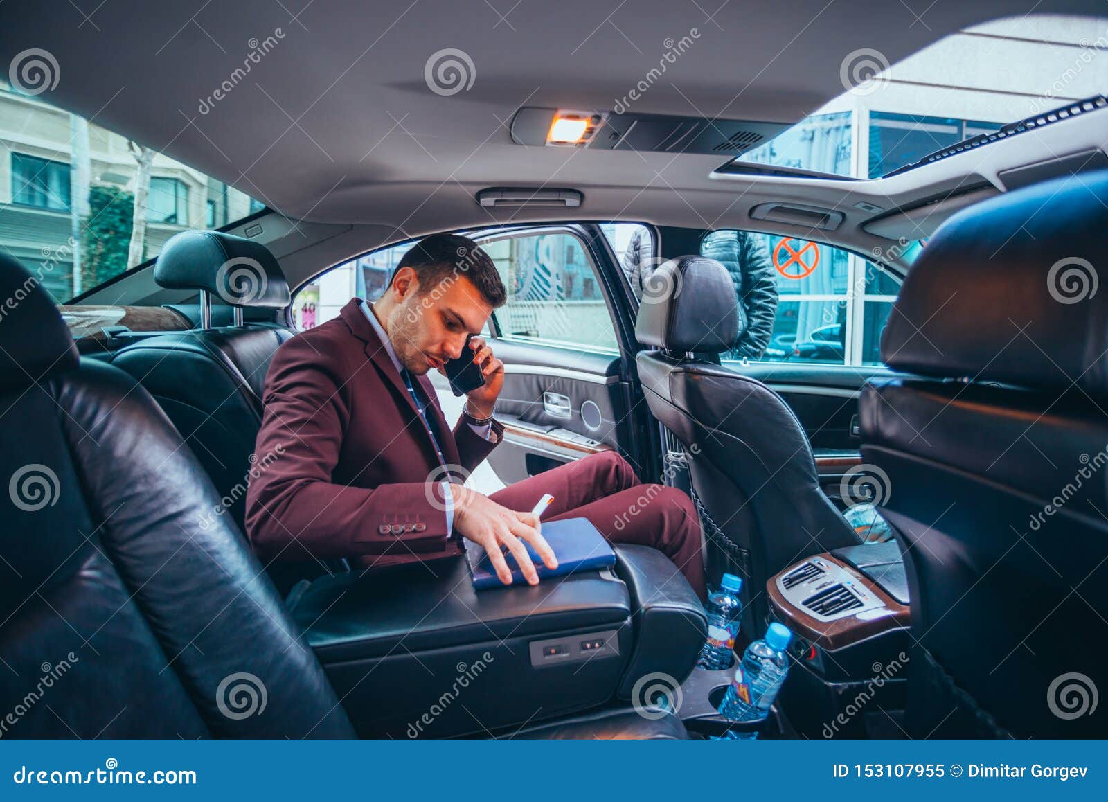 Businessman Sitting in a Limo while Talking on His Phone Reading His ...