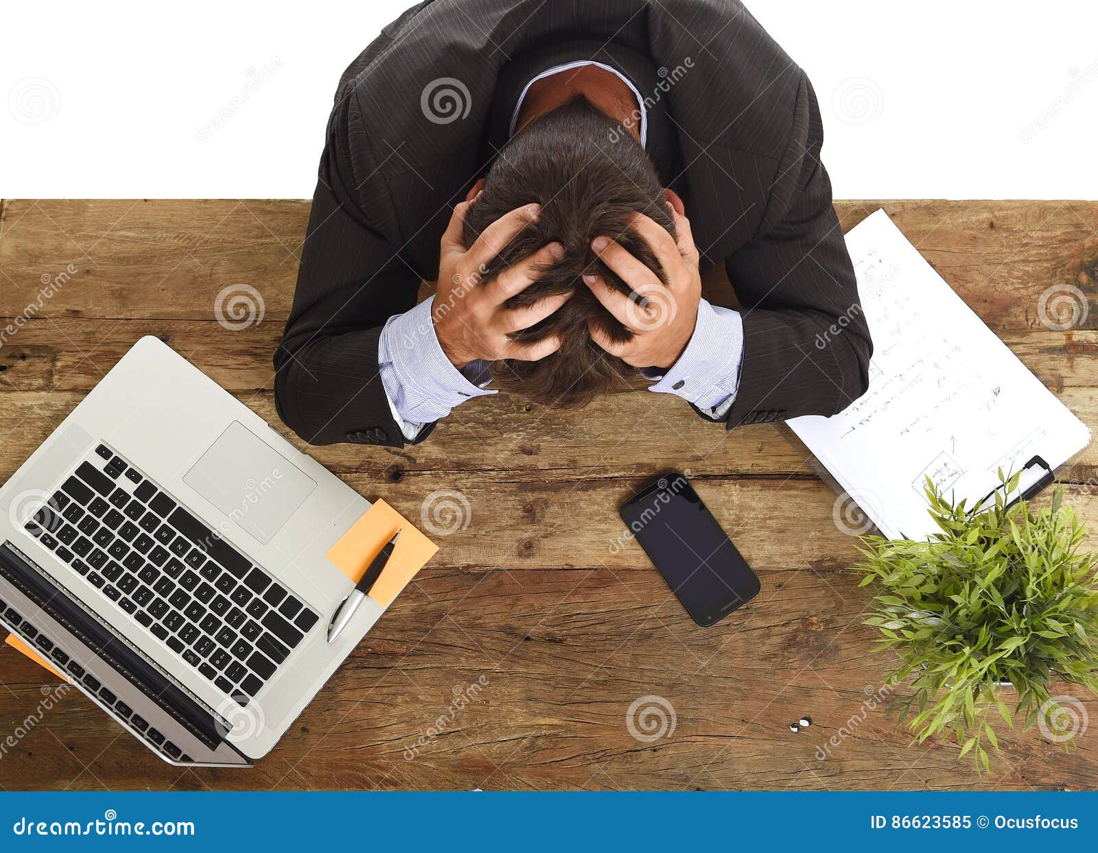 Businessman Sitting At Office Desk With Hands On His Head Crying