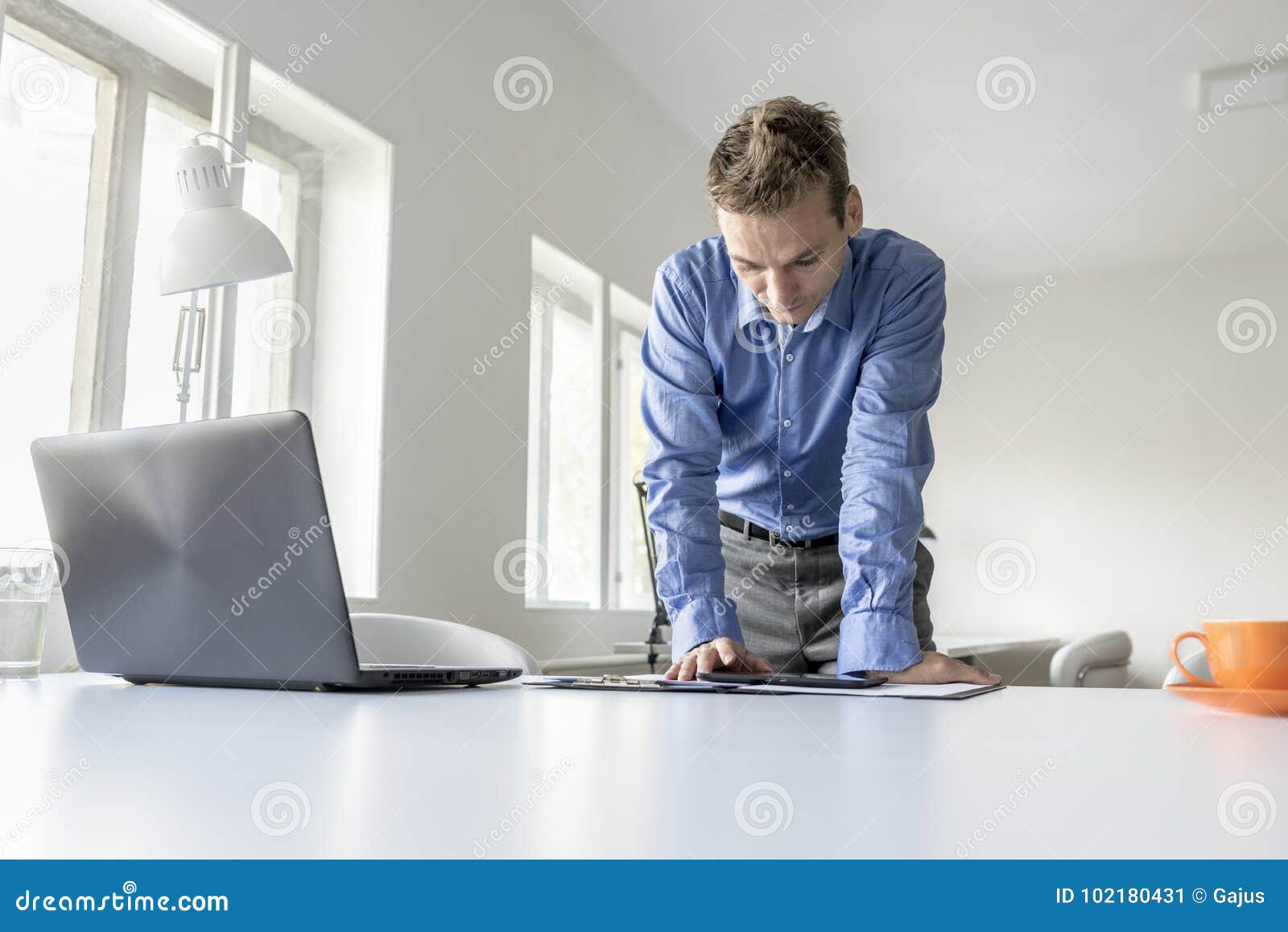 Businessman Standing Leaning on His Desk Reading a Tablet Compu Stock ...