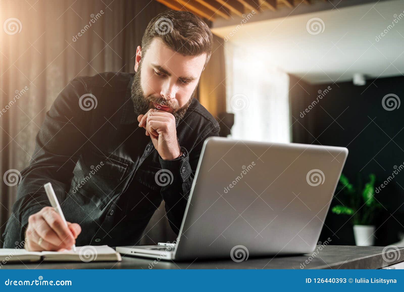 Businessman is Standing Near Computer, Working on Laptop, Making Notes ...
