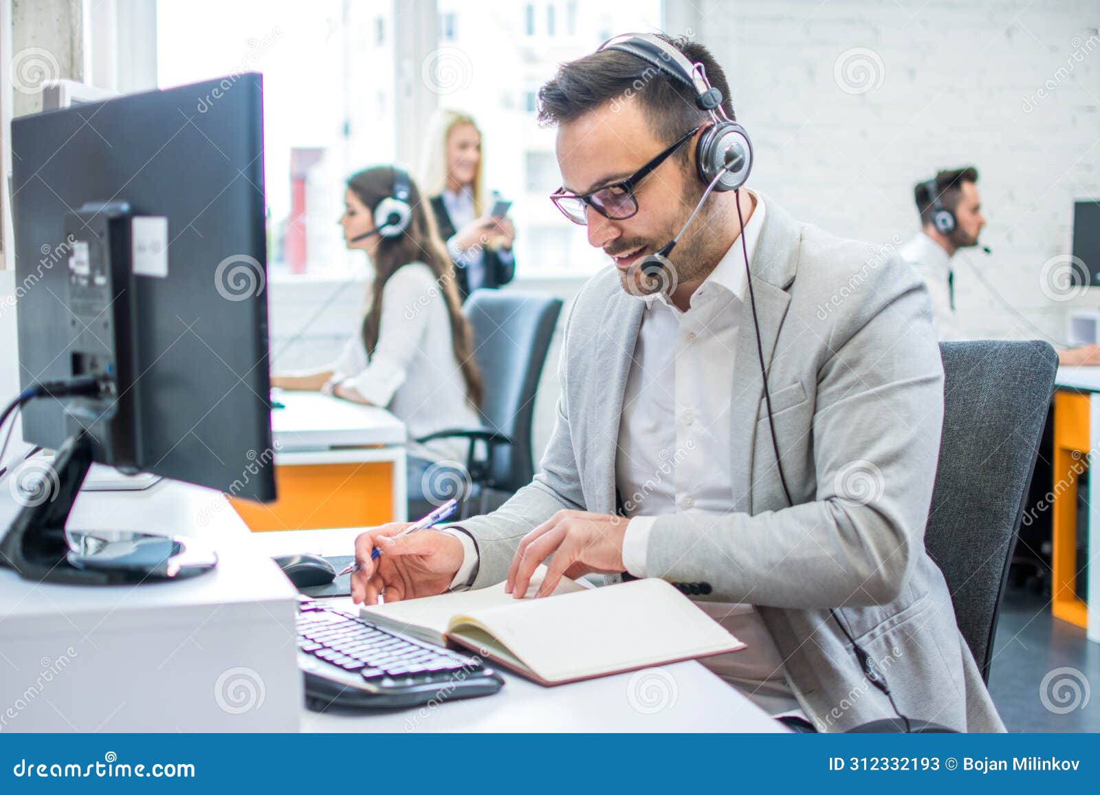 Businessman Taking Notes while Talking with Customer Using Headphones ...