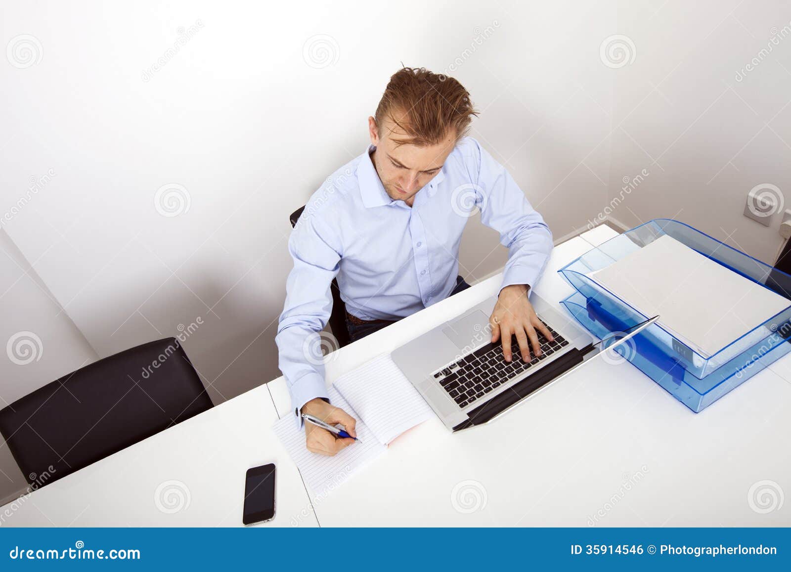 Businessman Taking Notes while Using Laptop in Office Stock Photo ...