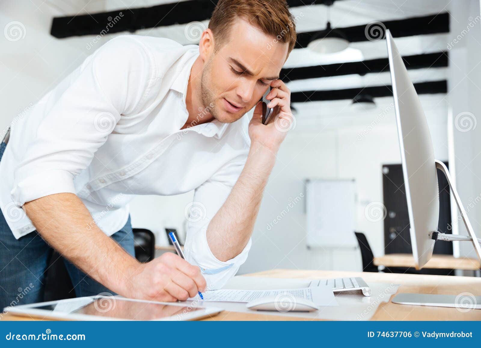 Businessman Talking on Cell Phone and Writing in Office Stock Photo ...