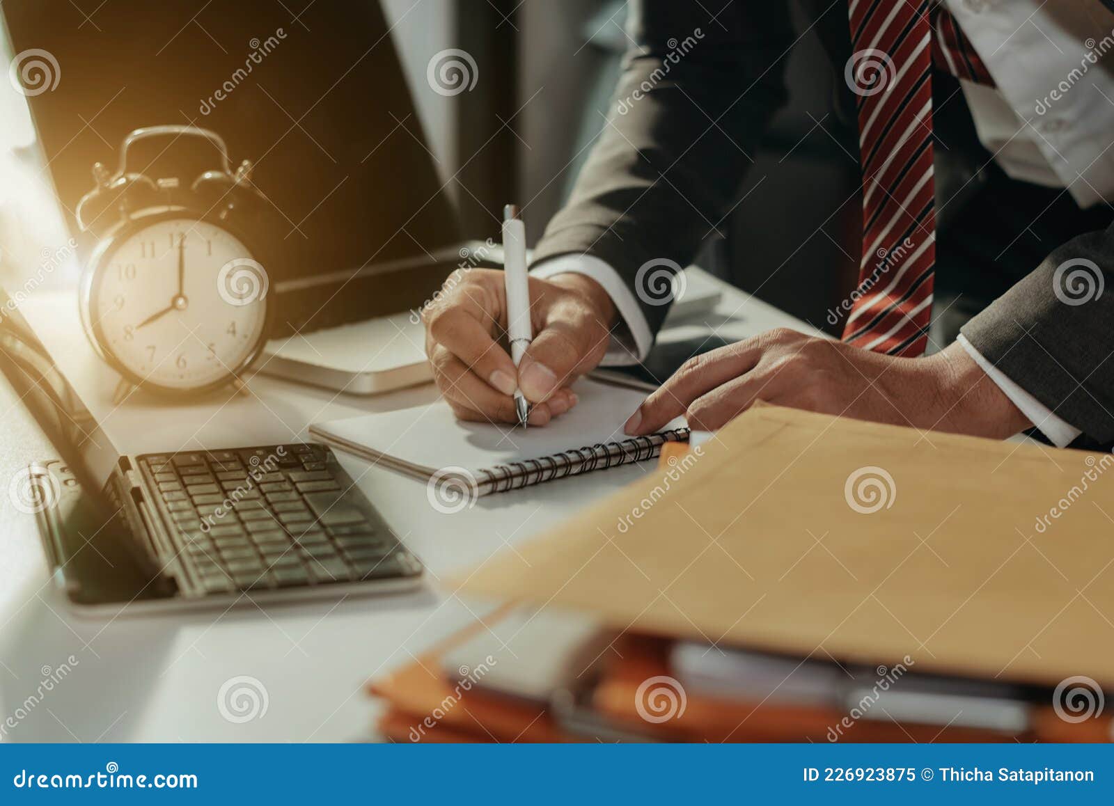 Businessman Use a Laptop Computer and Take Notes in the Notebook at the ...