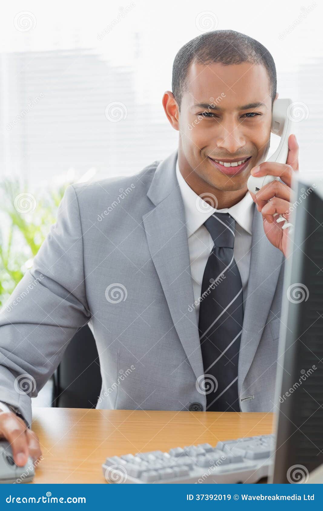 Businessman Using Computer and Phone at Office Desk Stock Image - Image ...