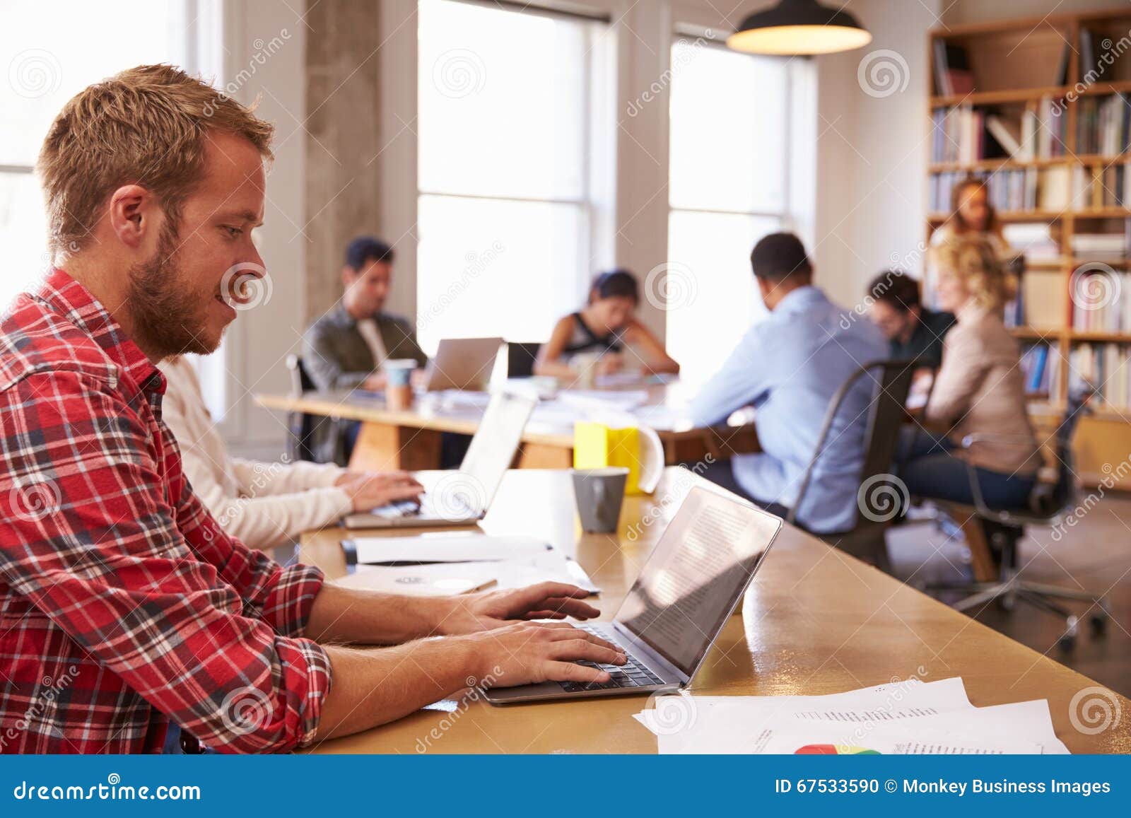 Businessman Using Laptop at Desk in Busy Office Stock Photo - Image of ...