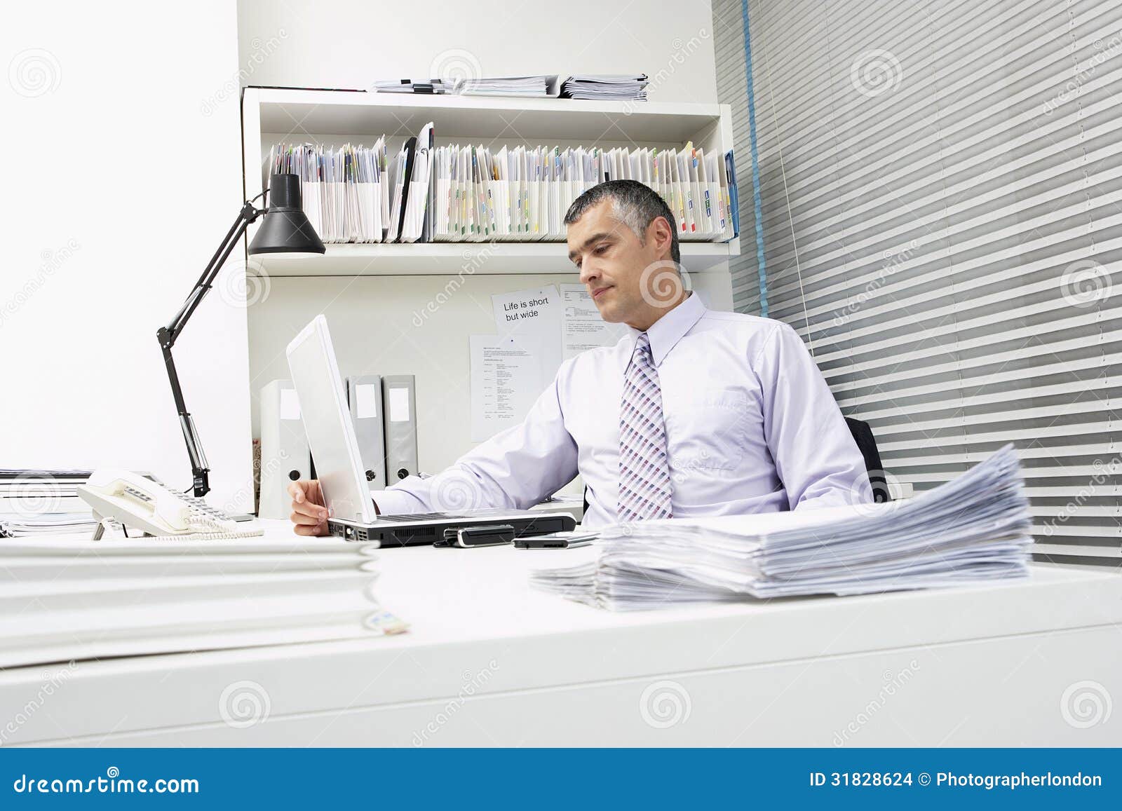 Businessman Using Laptop with Paperwork at Desk Stock Photo - Image of ...