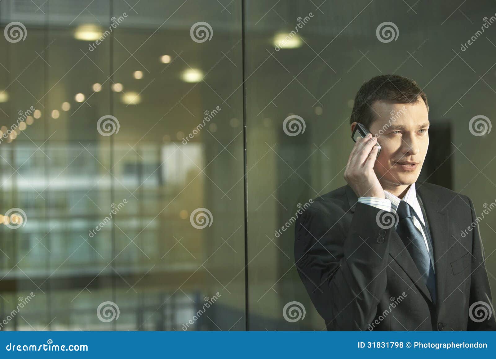 Businessman Using Mobile Phone while Standing Against Glass Wall Stock ...
