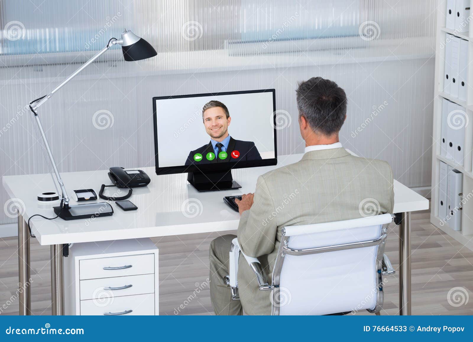 Businessman Videoconferencing with Partner on Computer at Desk Stock ...