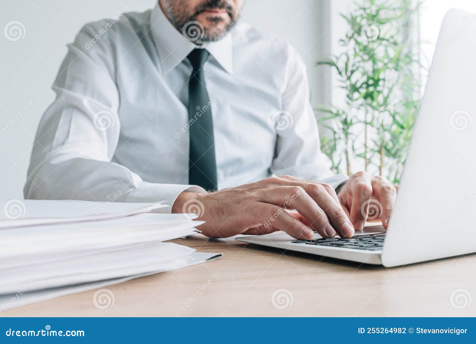 Businessman Working on Laptop Computer with Paperwork Pile on Office ...