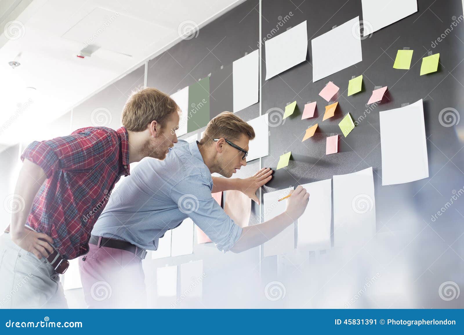 Businessmen Analyzing Documents on Wall in Office Stock Image - Image ...