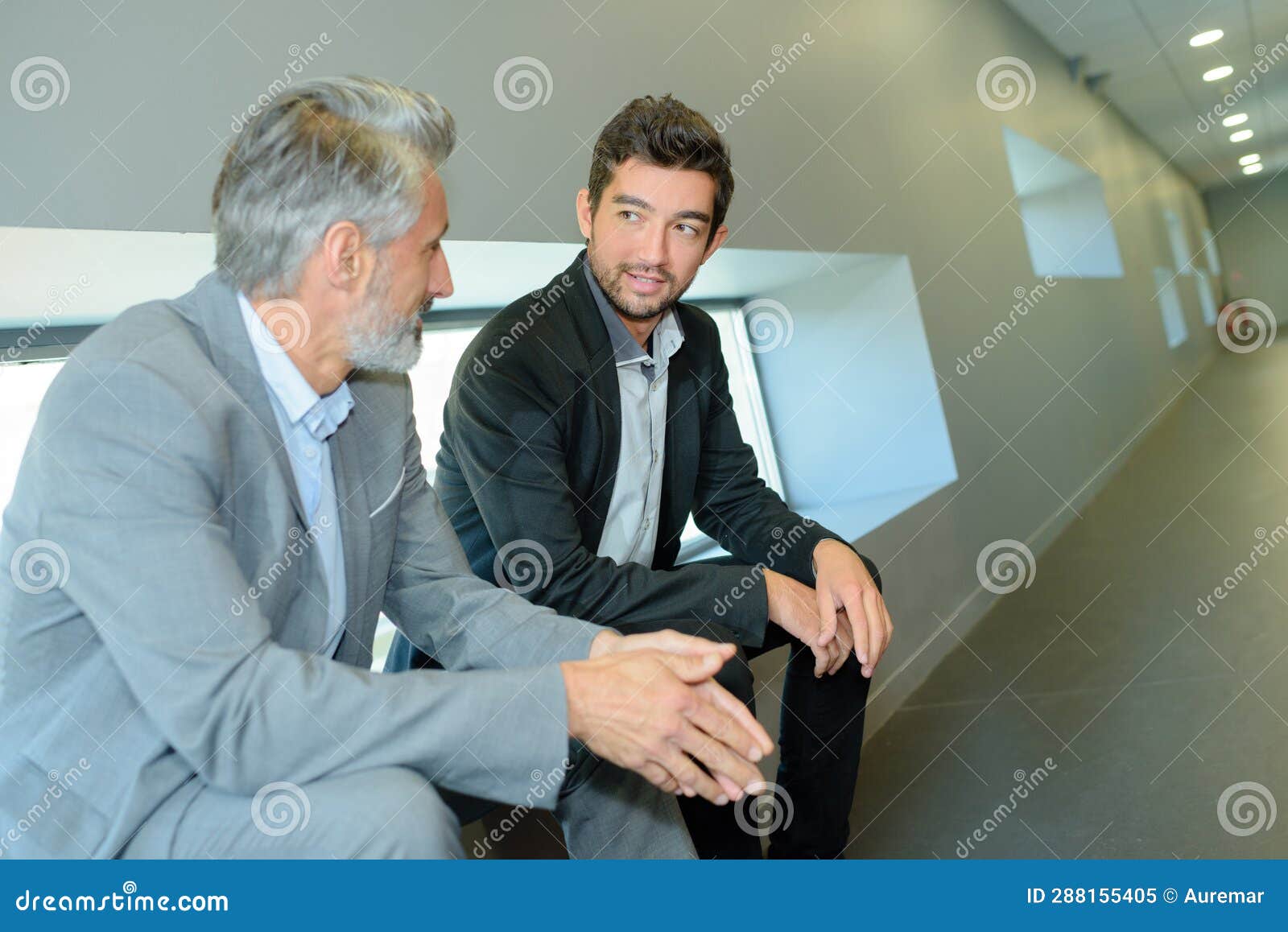 Businessmen Discussing Work at Office Building Corridor Stock Image ...