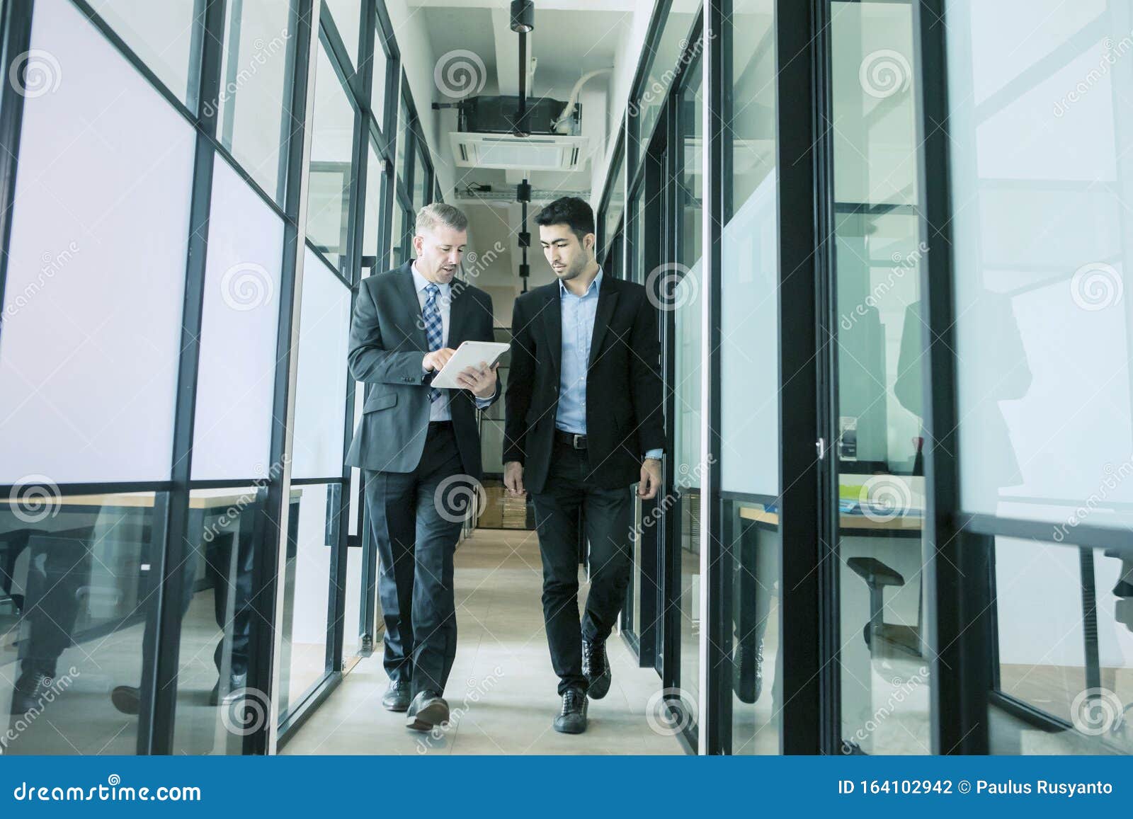 Businessmen Discussing Work while Walking in Office Corridor Stock ...