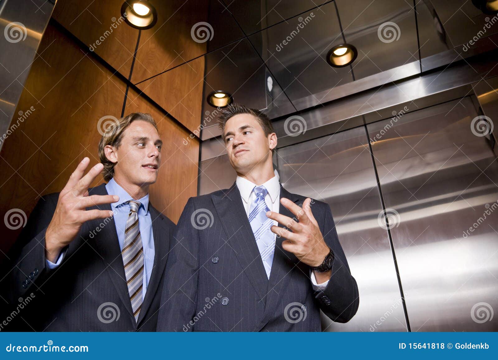 Businessmen in Elevator Conversing Stock Photo - Image of male, workers ...