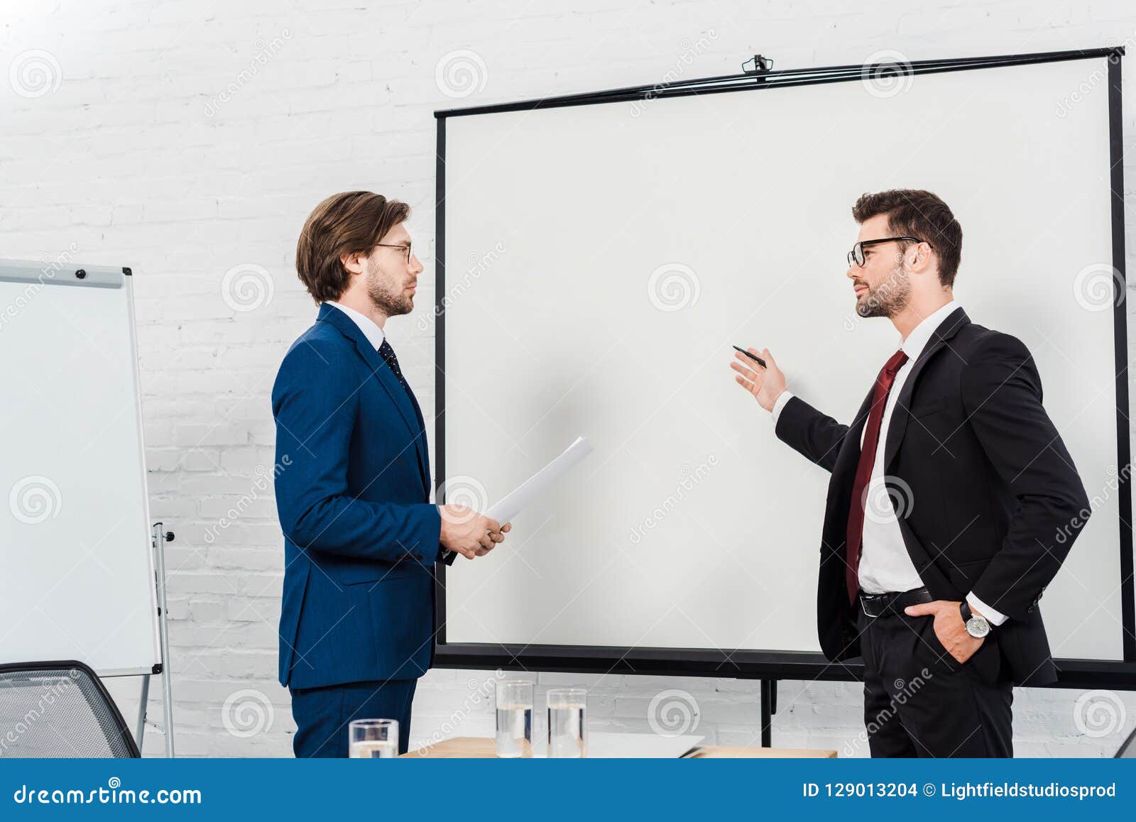 Businessmen Having Conversation and Pointing at Presentation Board ...
