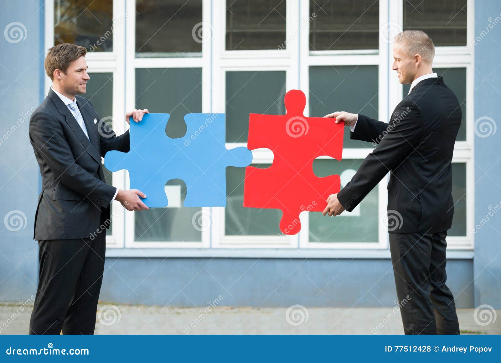 Businessmen Joining Jigsaw Pieces Outside Office Stock Photo - Image of ...