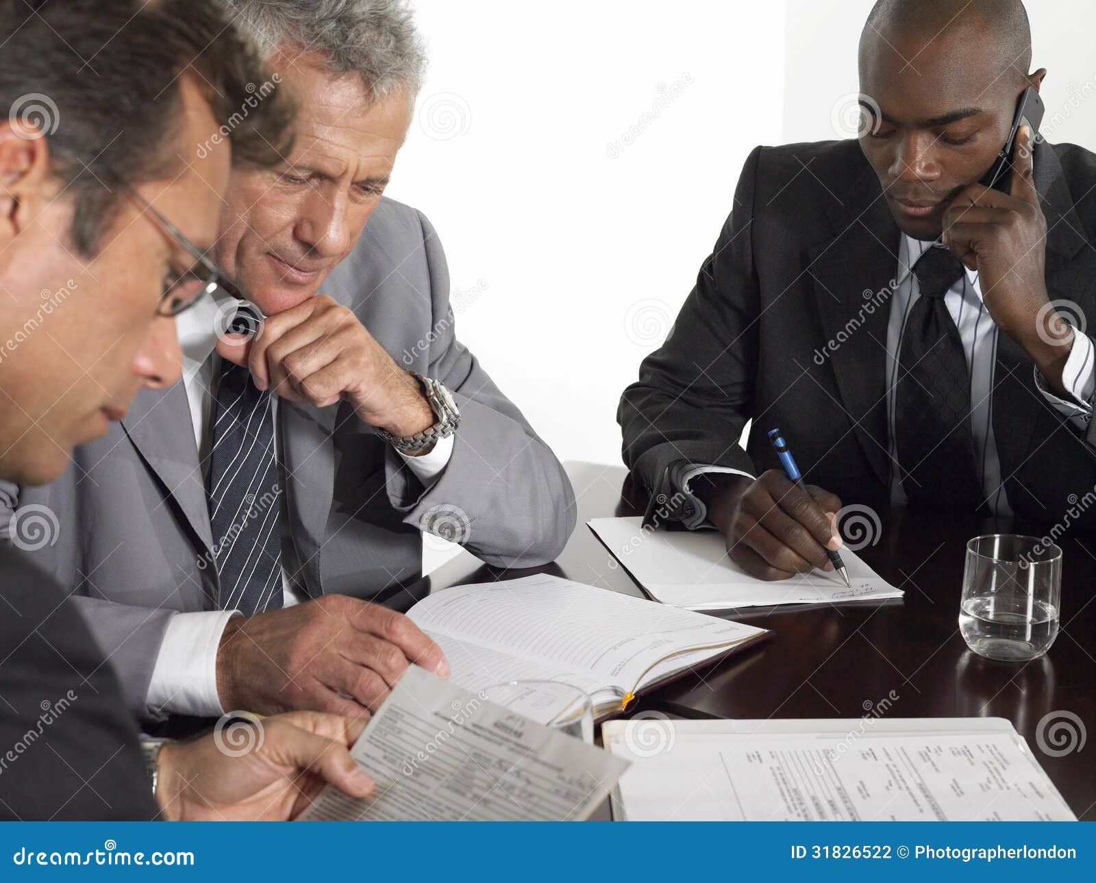 Businessmen with Paperwork at Conference Table Stock Photo - Image of ...