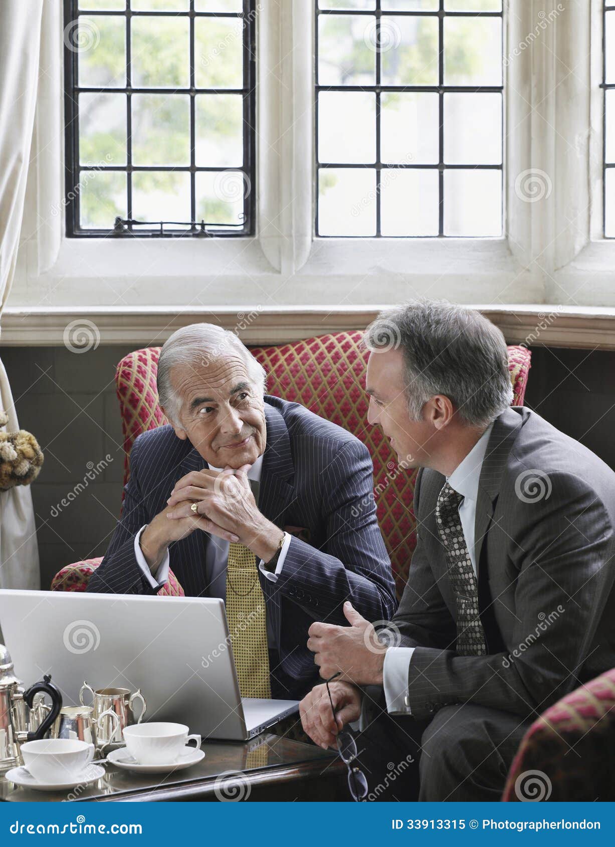 Businessmen Talking Over Laptop in Lobby Stock Image - Image of ...