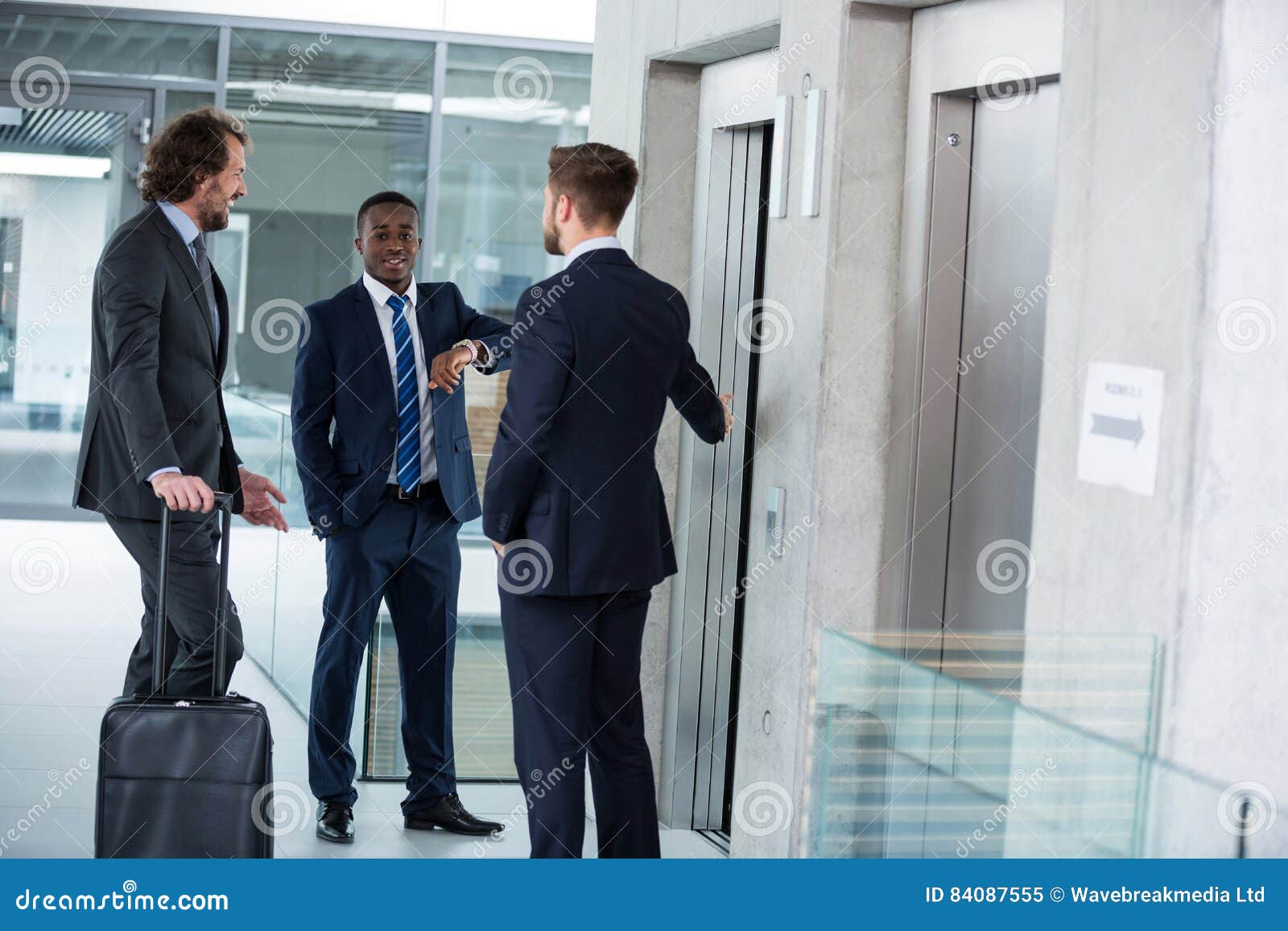 Businessmen Talking while Waiting for Elevator Stock Image - Image of ...