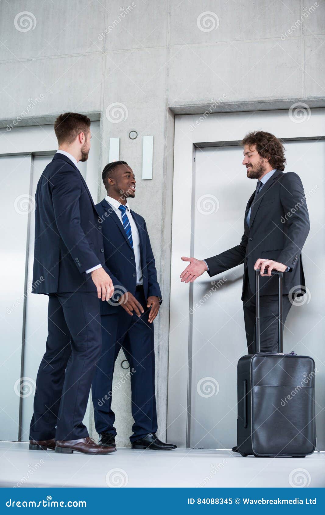Businessmen Talking while Waiting for Elevator Stock Image - Image of ...