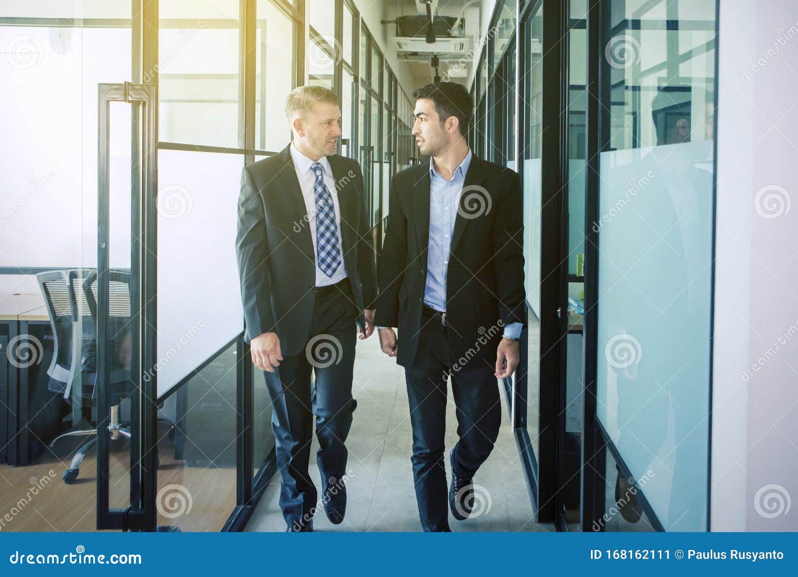 Businessmen Talking while Walking Down the Hallway Stock Image - Image ...