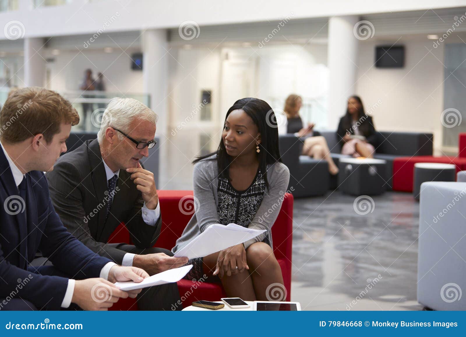 Businesspeople Discuss Document in Lobby of Modern Office Stock Photo ...