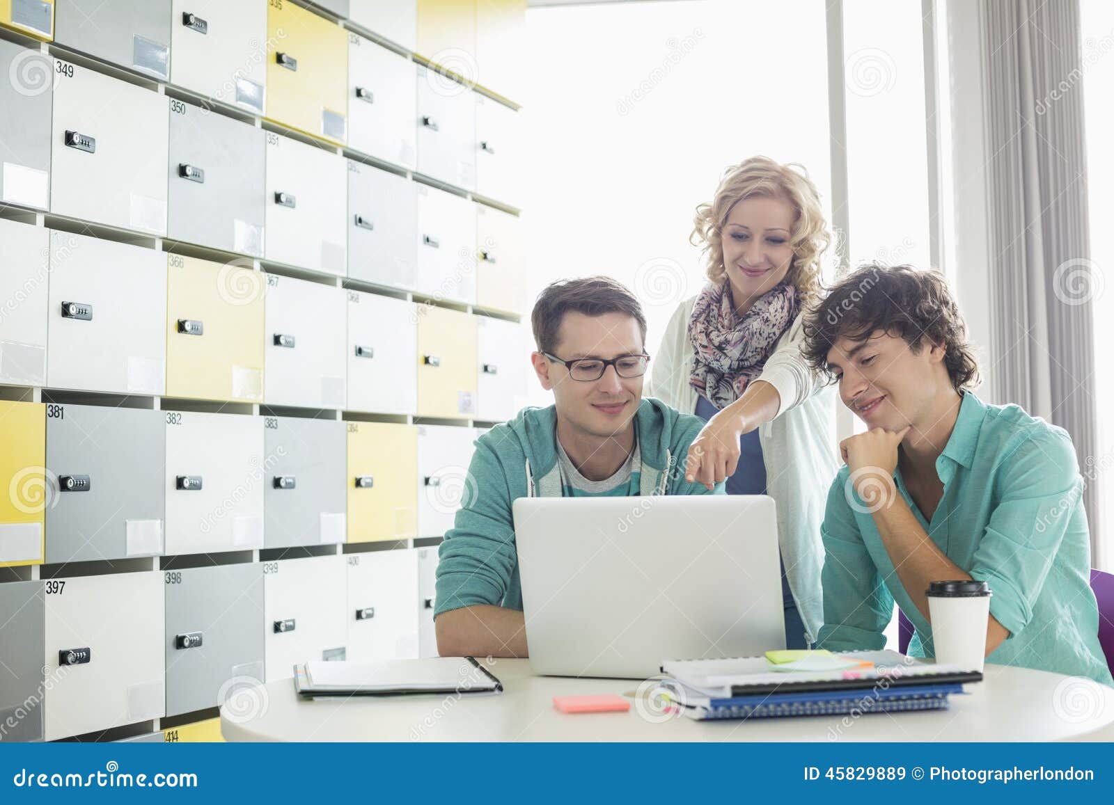 Businesspeople Using Laptop at Table in Locker Room at Creative Office ...
