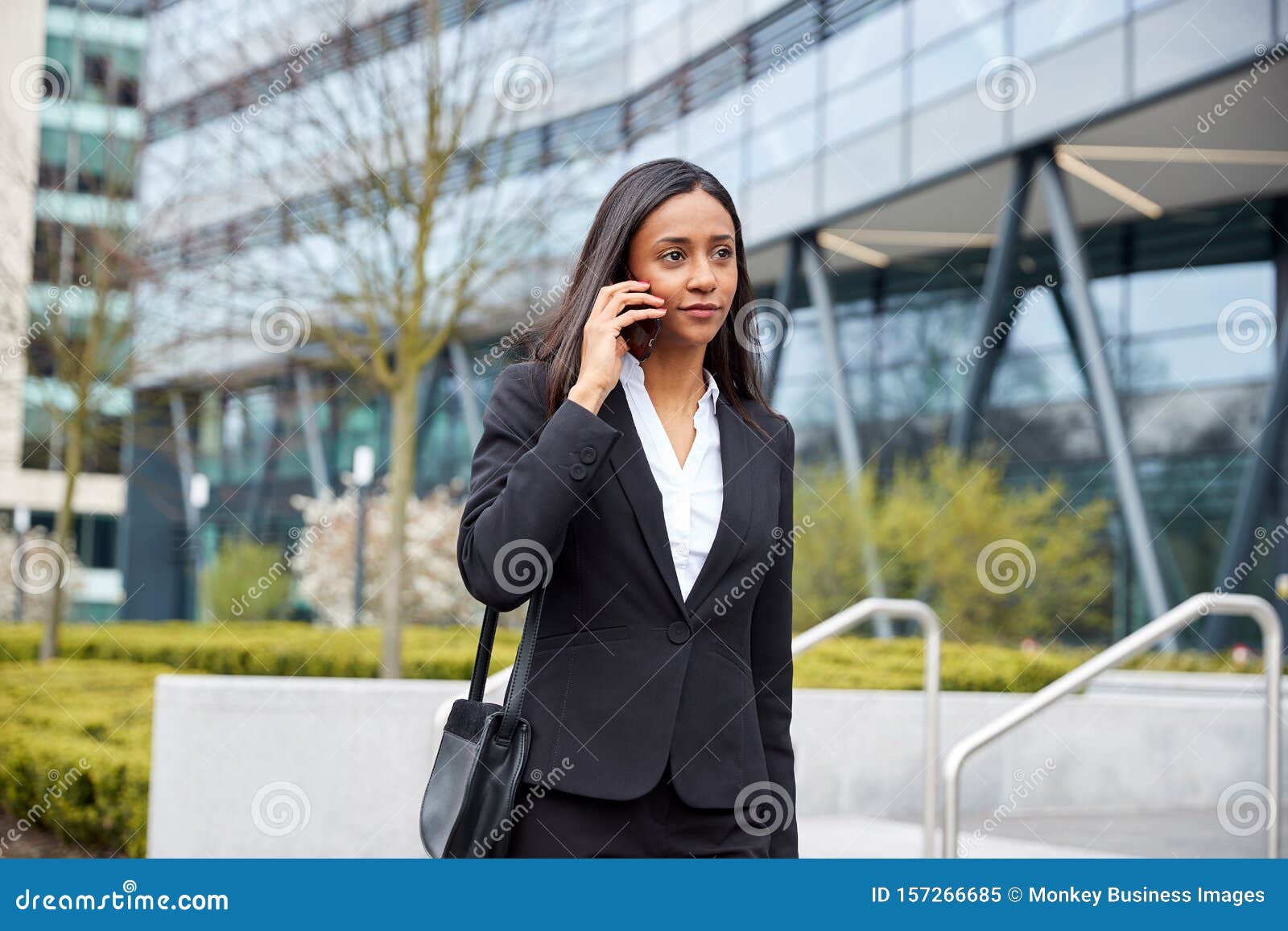 Businesswoman Commuting To Work Talking On Mobile Phone Outside Modern