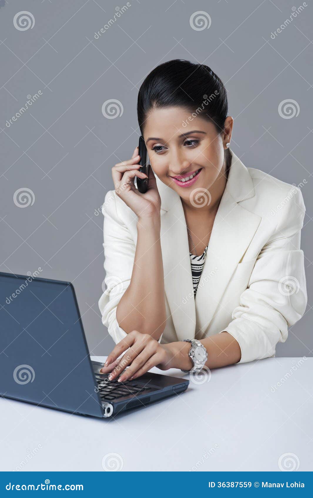 Businesswoman Using Laptop and Talking on a Mobile Phone Stock Image ...