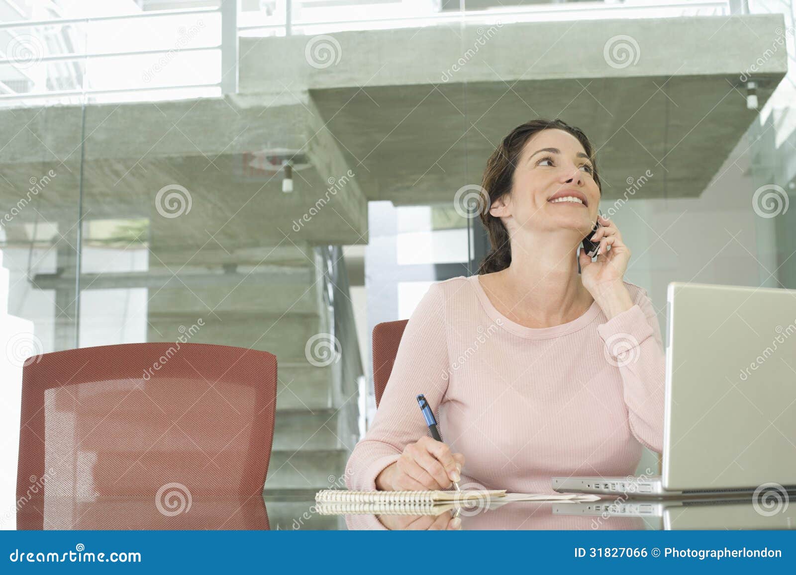 Businesswoman Using Mobile Phone while Writing on Notepad Stock Photo ...