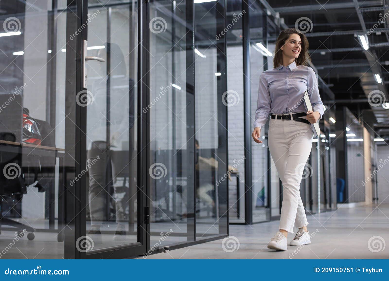 Businesswoman Walking Along the Office Corridor with Documents Stock ...