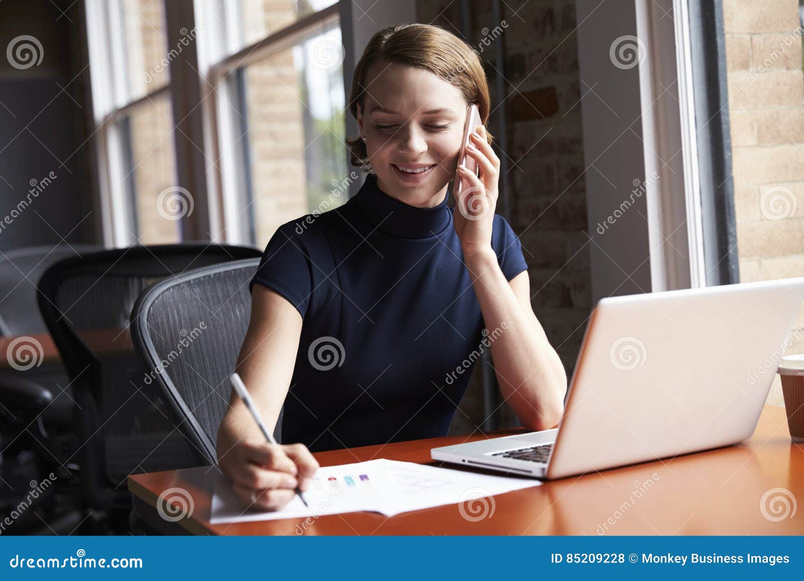 Businesswoman Working on Laptop and Making Phone Call Stock Photo ...