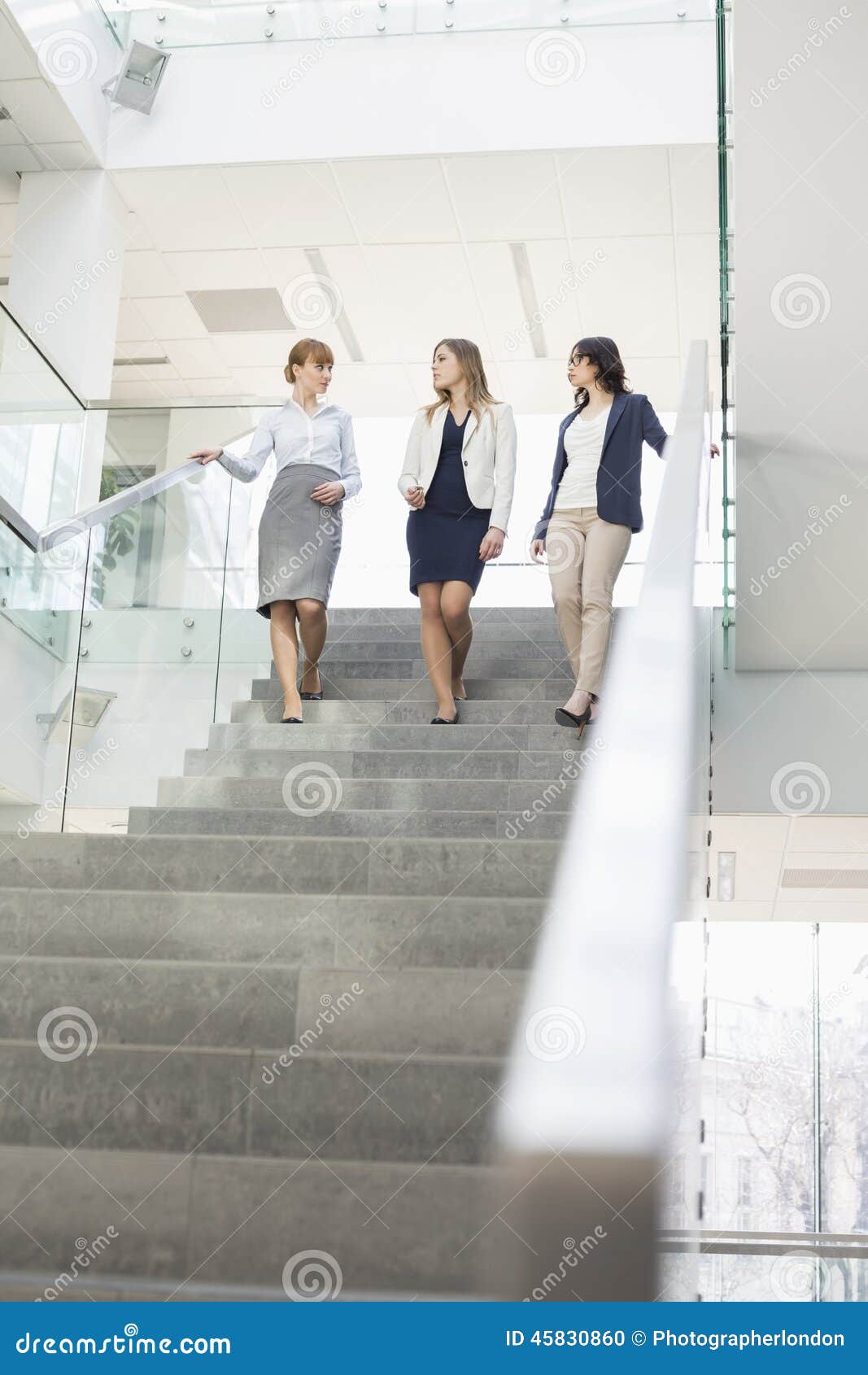 Businesswomen Conversing while Moving Down Steps in Office Stock Photo ...