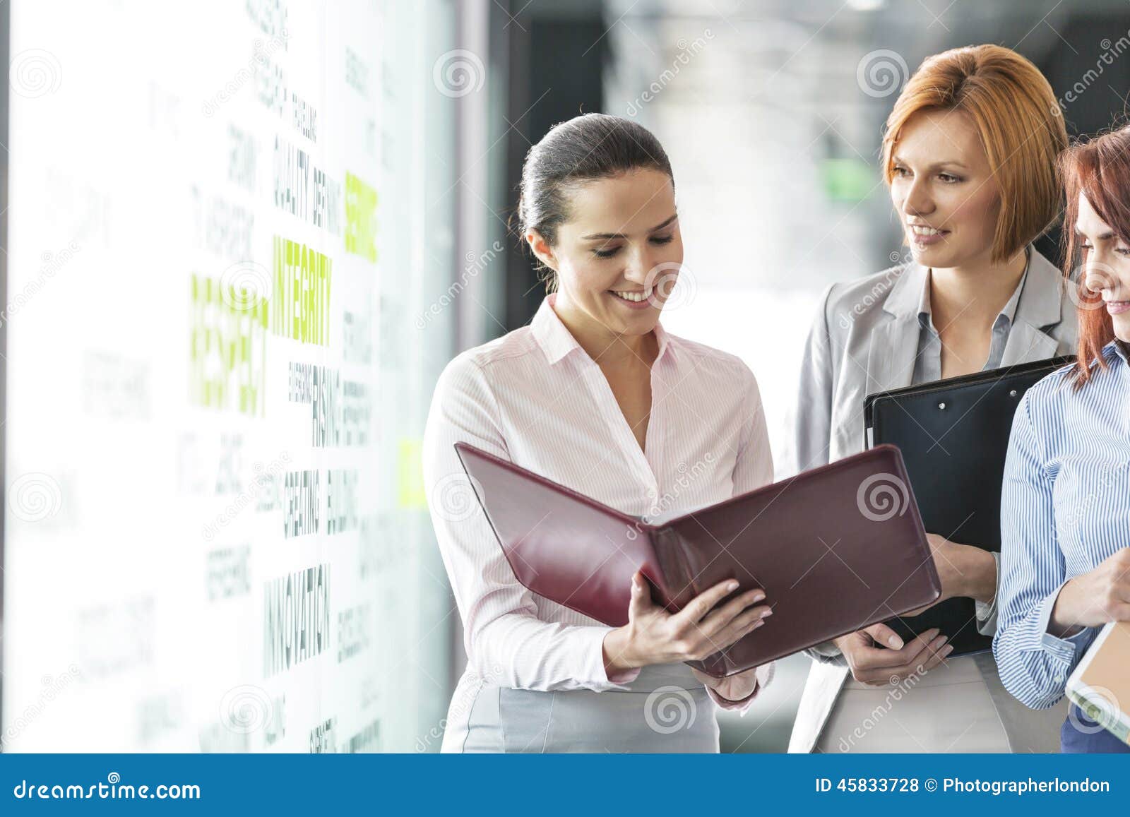 Businesswomen with File Folders Discussing in Office Corridor Stock ...