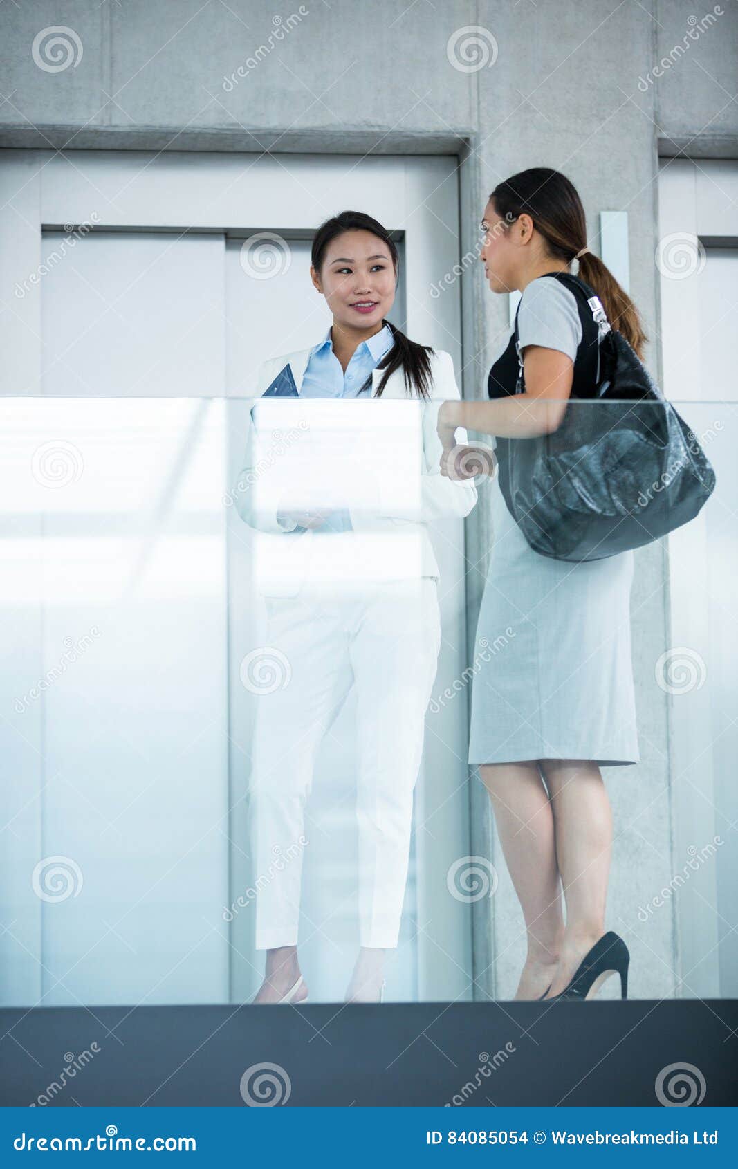 Businesswomen Standing by Elevator and Having a Conversation Stock ...