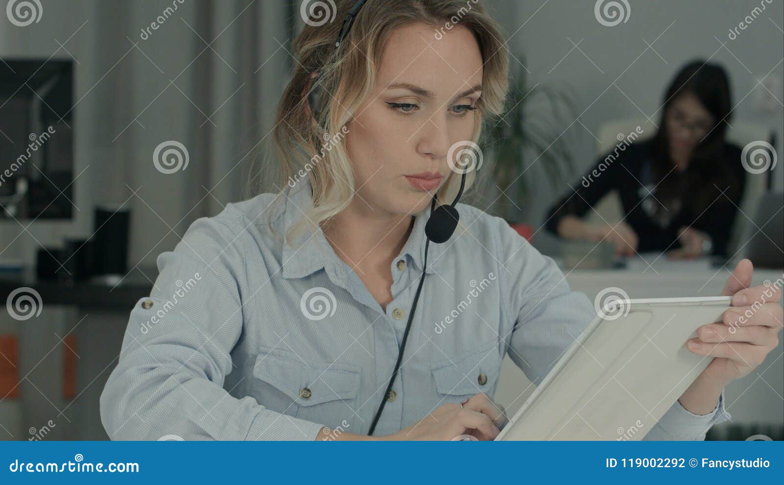 Busy Call Center Agent Using Digital Tablet on a Call at Her Workplace ...