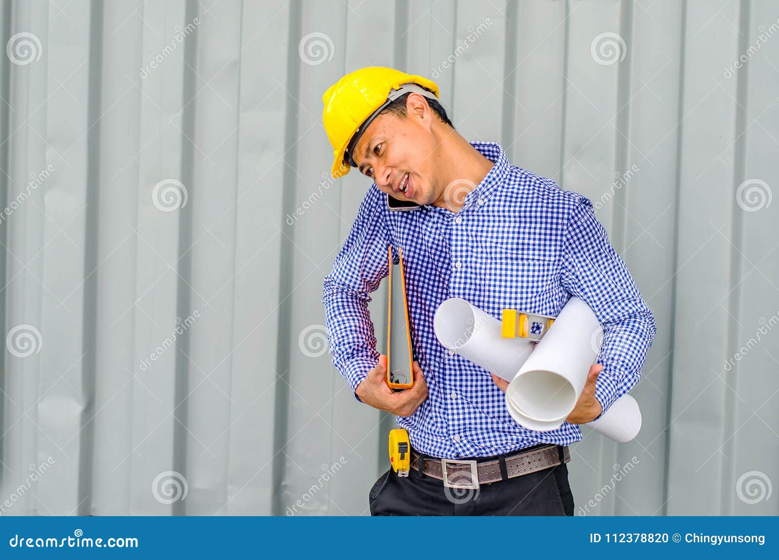 Busy Construction Engineer Talking on Phone while Carrying Blueprints ...