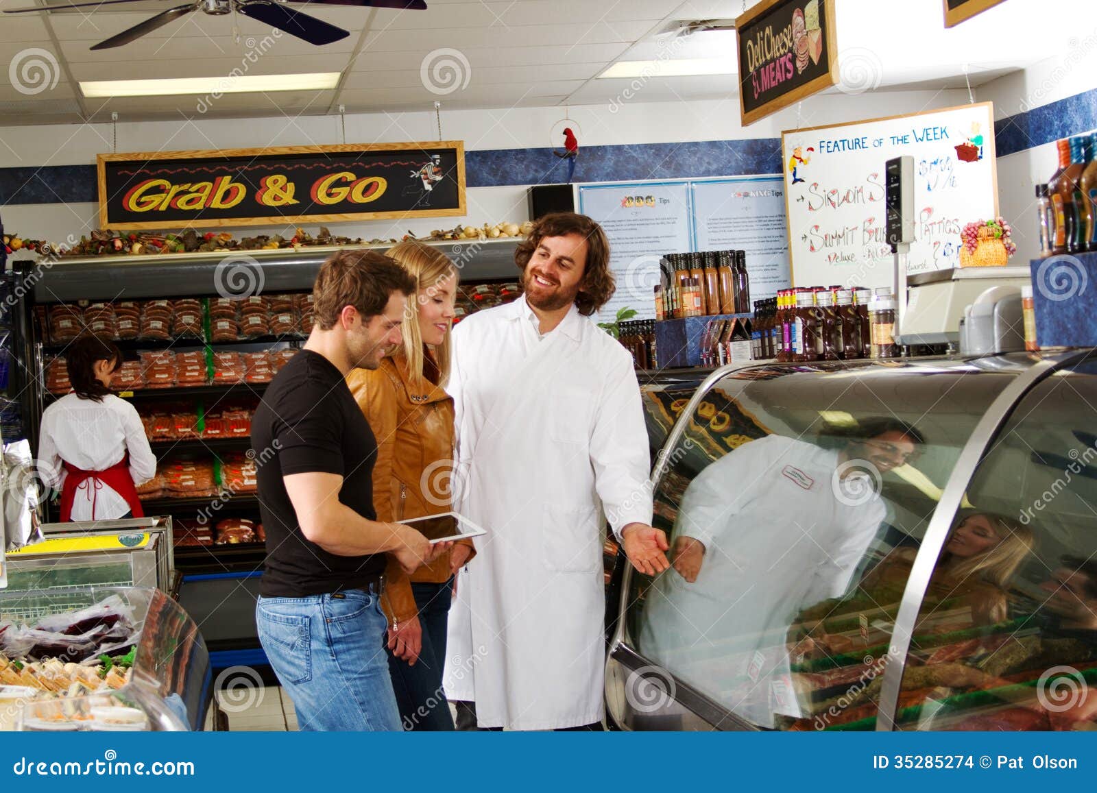 Butcher Explaining Various Meats To Couple Stock Photo - Image of ...