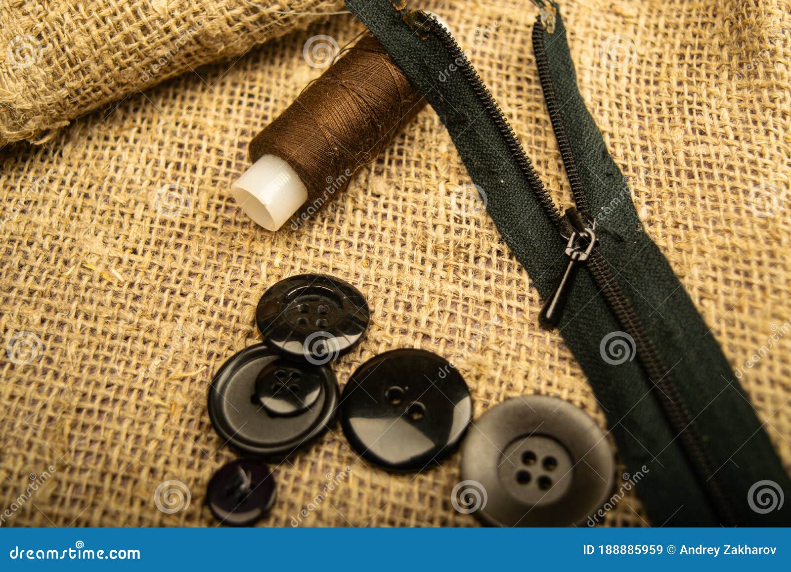 Buttons of Different Sizes, a Spool of Thread and a Zipper on a Burlap ...