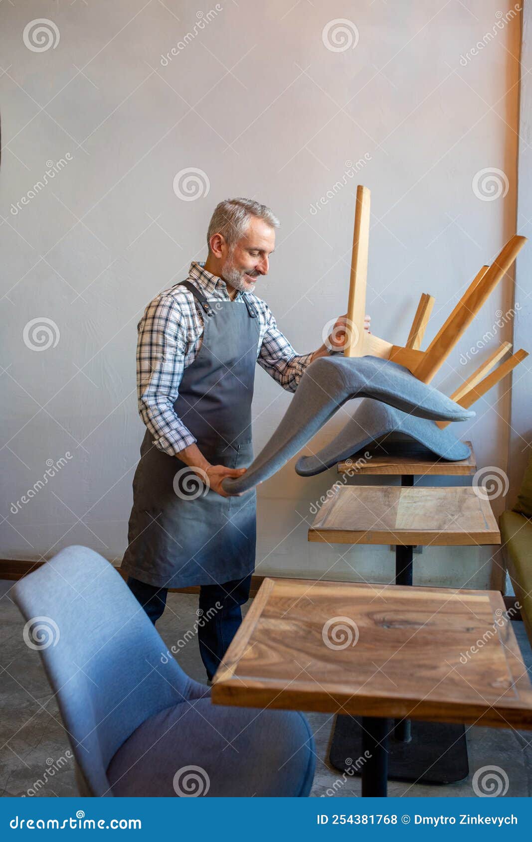Man in Apron Putting Chairs on the Table in a Cafe Stock Photo - Image ...