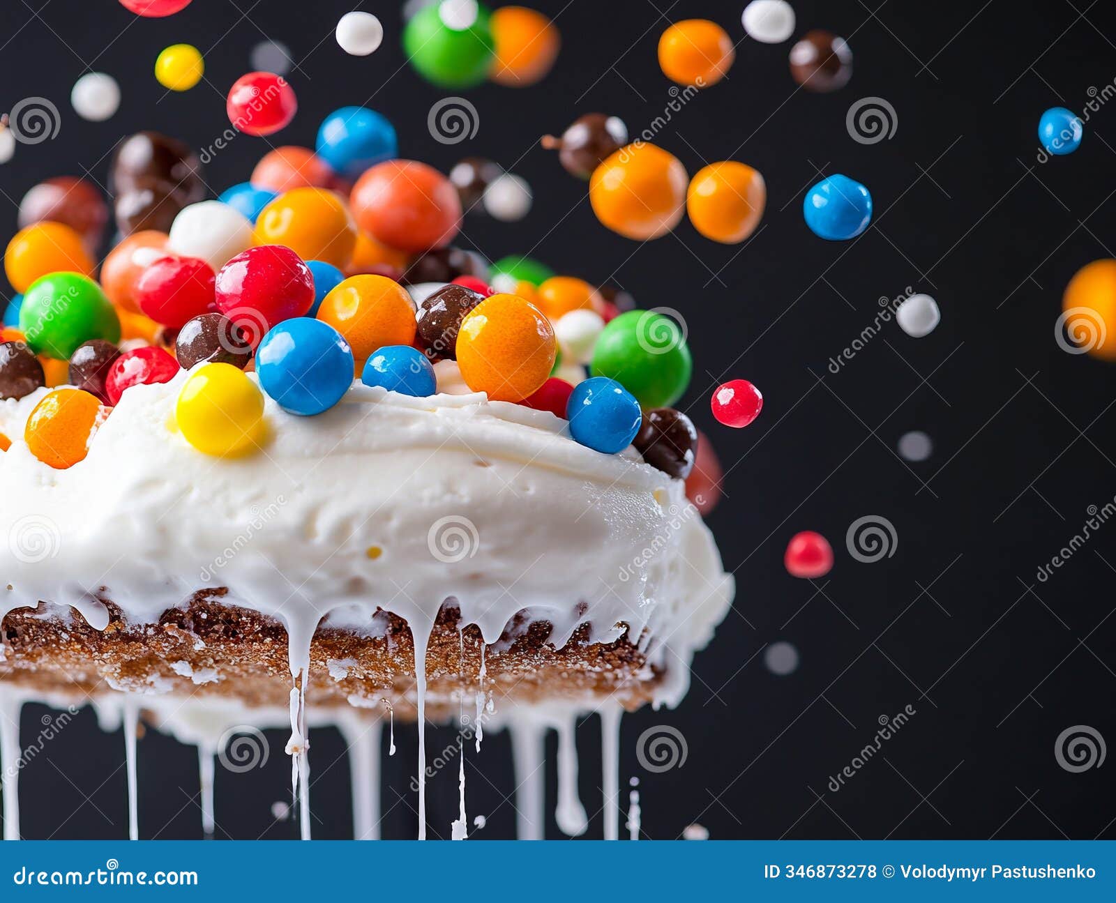 A Cake with White Frosting and Colorful Candies Falling from it Stock ...
