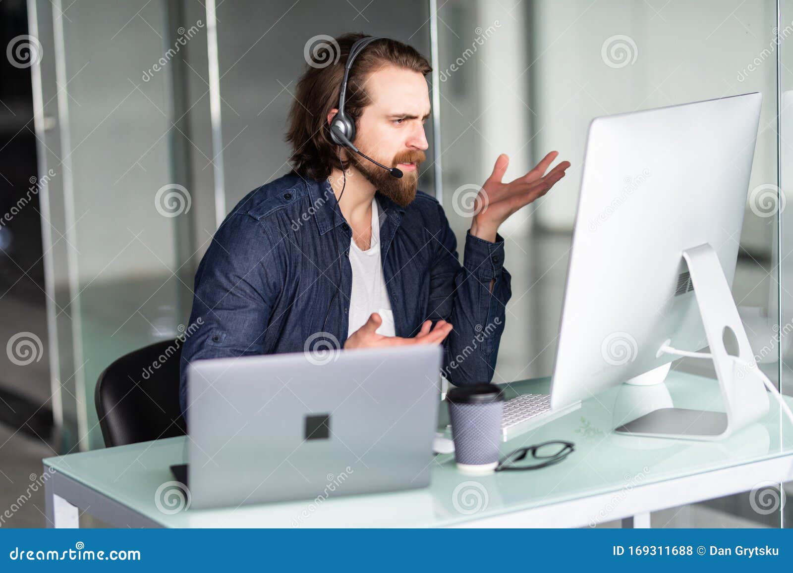 Angry Call Center Operator Working at His Desk on Computer and Laptop ...