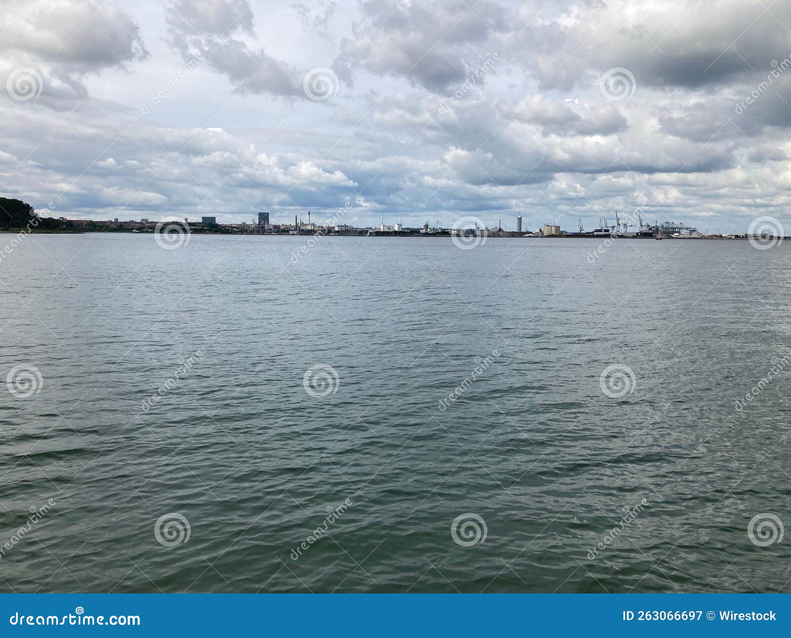 Calm Coast and a Harbor in the Background during a Cloudy Day Stock ...