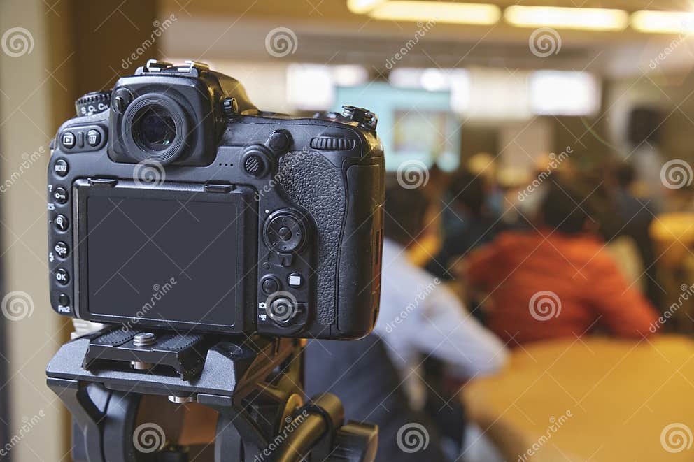 A Camera is Pointed at a Group of People Sitting at a Table Stock Photo ...