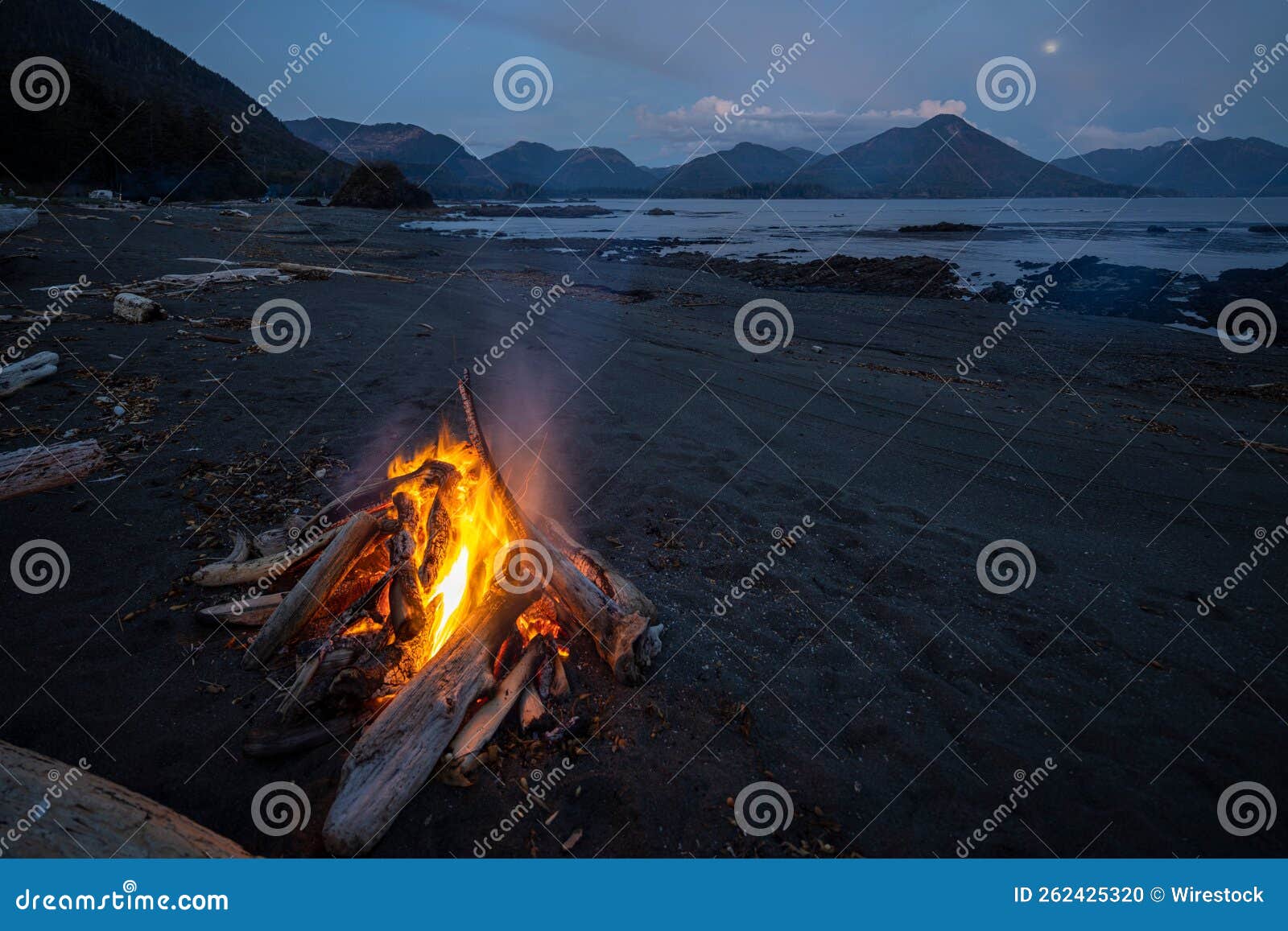 Campfire on Calm Lake Shore with Mountains in the Background Stock ...