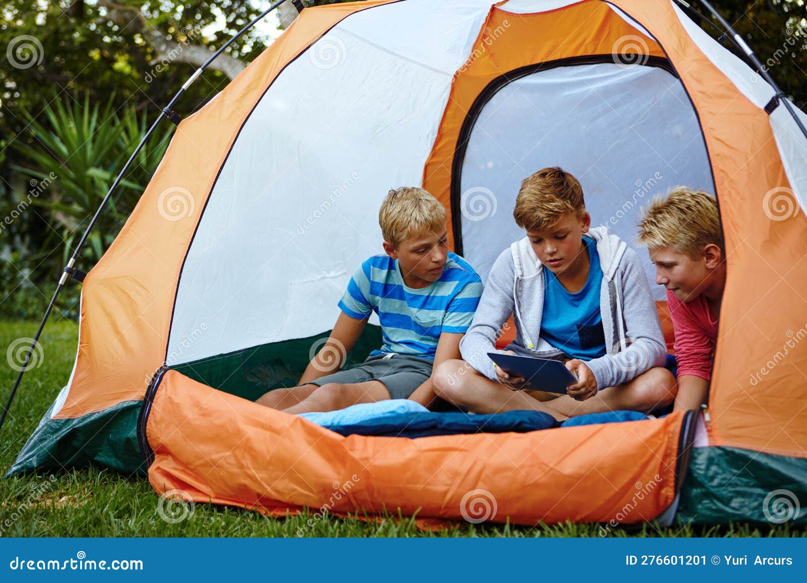 Camping with Technology. Three Young Boys Using a Digital Tablet while ...