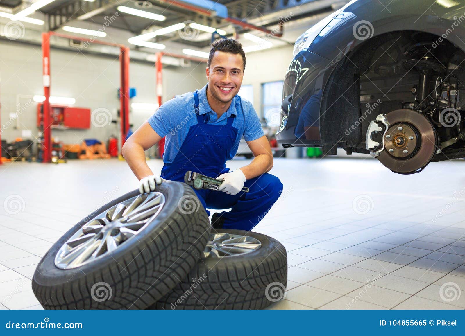 Car Mechanic Crouching Down by a Pair of Wheels Stock Image - Image of ...