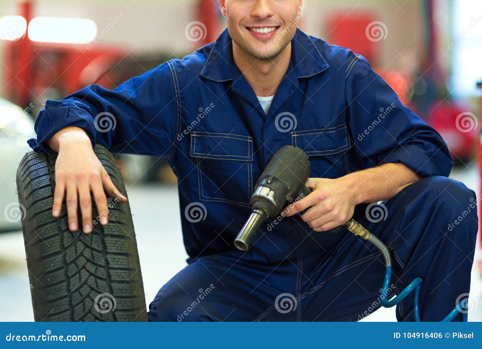 Car Mechanic Crouching Down by a Tire Stock Photo - Image of autoshop ...
